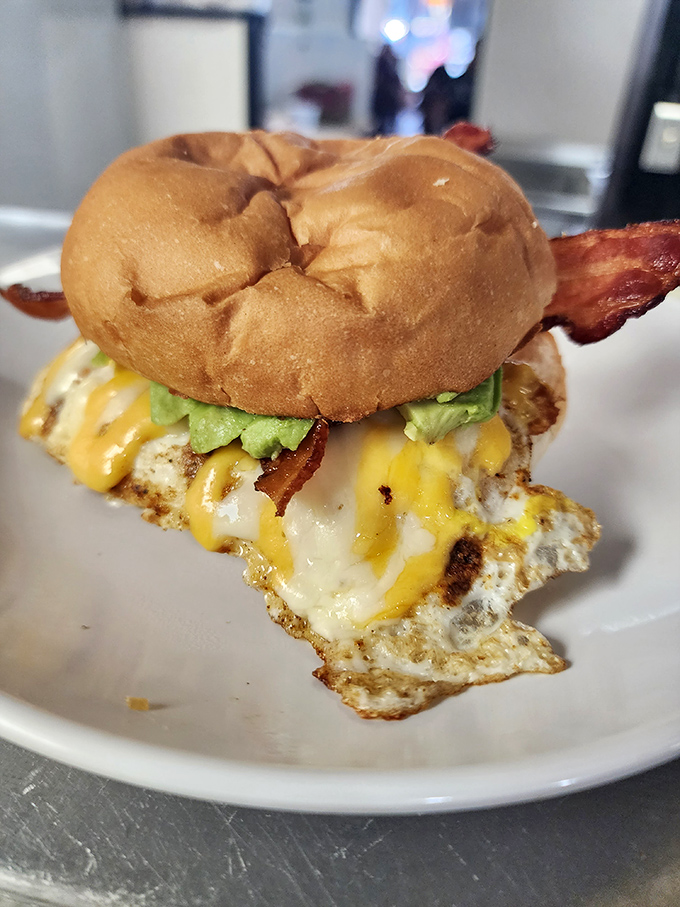 A breakfast sandwich that understands the importance of proper architecture – egg, cheese, bacon, and avocado in golden-ratio perfection.