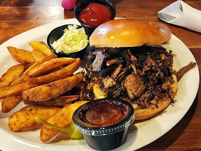 The pulled pork sandwich in its natural habitat – surrounded by golden fries and coleslaw that actually deserves to be eaten.
