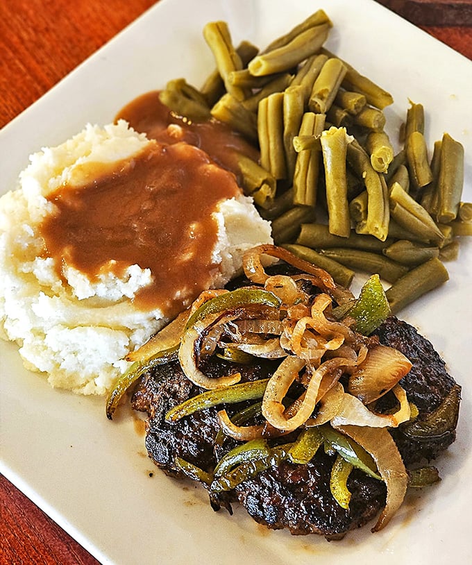 A steak that's found its perfect companions: crisp green beans and cloud-like mashed potatoes. The sautéed onions and peppers are wearing their caramelized best.