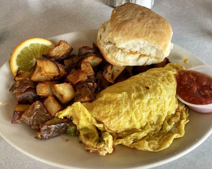 This omelet doesn't just contain ingredients; it showcases them—a supporting cast of home fries and biscuit complete the ensemble.