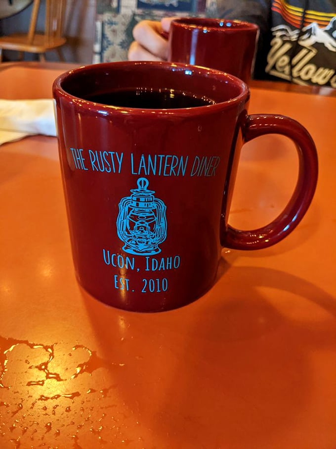 The diner's signature burgundy mug proudly displays its Ucon, Idaho heritage—established 2010, but carrying comfort food traditions that span generations.