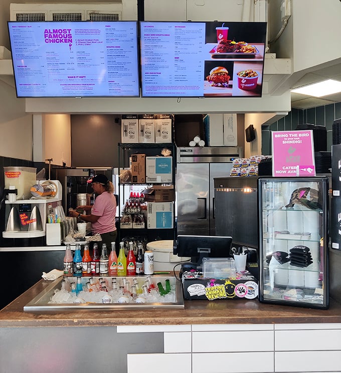 The digital menu boards loom above a counter stocked with colorful sodas – a modern touch in a place that honors traditional fried chicken techniques.