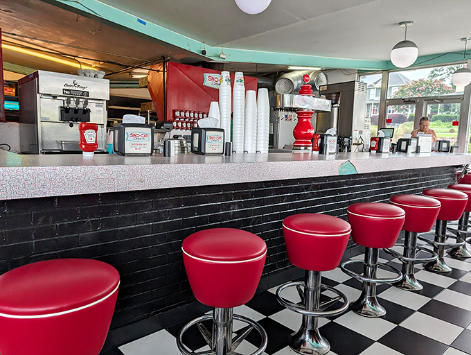 The counter view—where burger anticipation meets soda fountain artistry under the glow of vintage lighting.