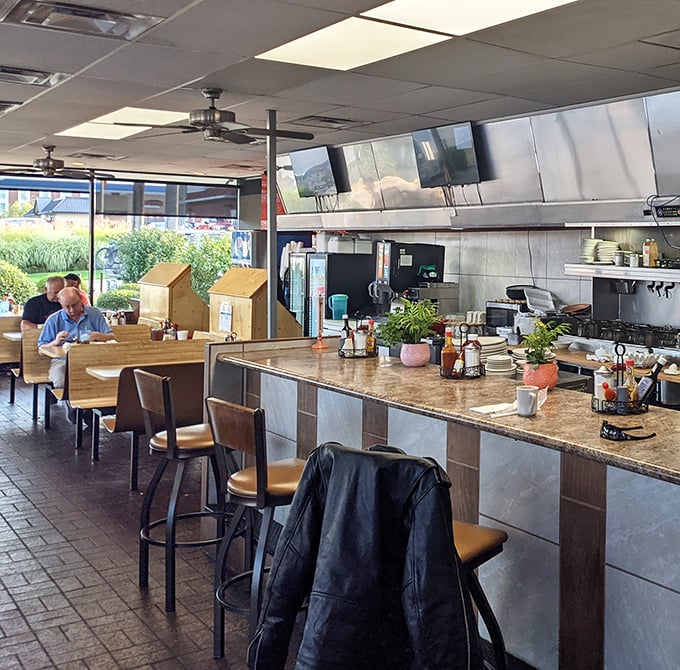 Counter seating that lets you watch the breakfast magic happen. Those wooden booths have probably heard more local gossip than any therapist in town.