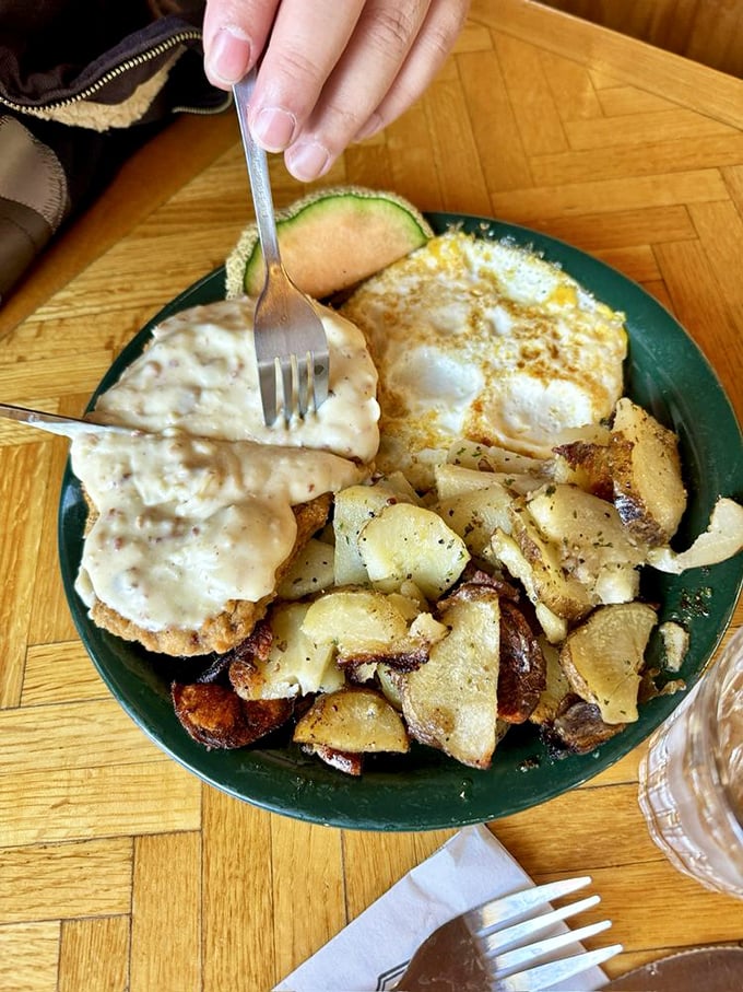 Country fried steak smothered in gravy with eggs and home fries—a breakfast so hearty it could fuel a day of chopping down pine trees.