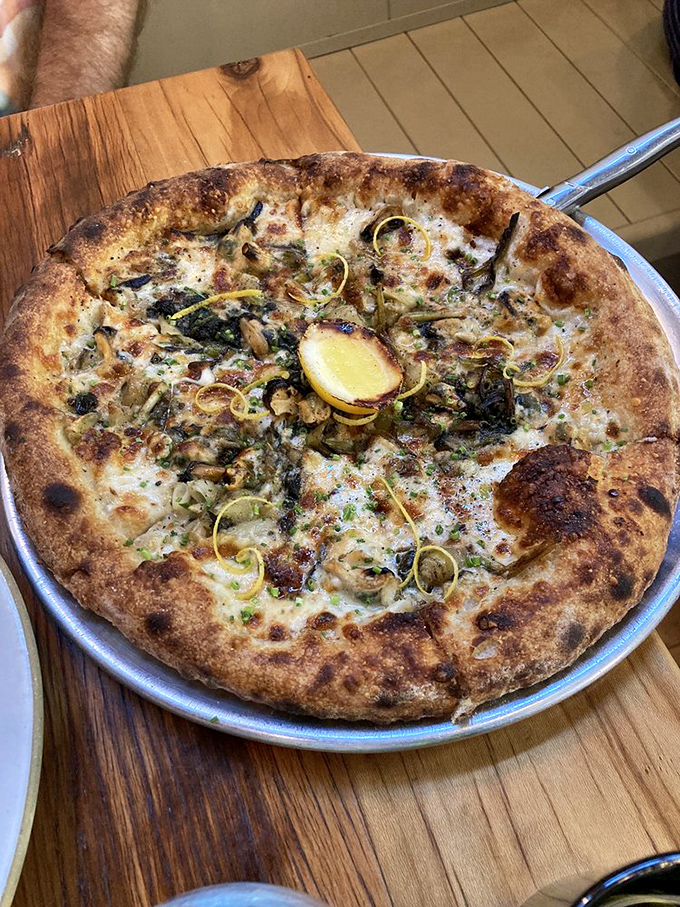 This white pizza with its golden crust and lemon accent isn't just food—it's edible sunshine that makes you wonder why you'd ever order anything else.