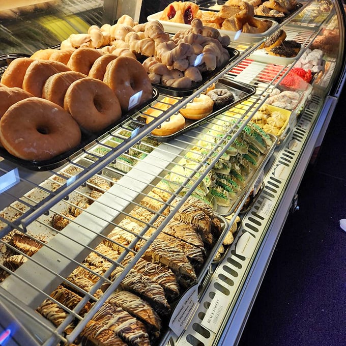 The pastry case stretches like a runway where each model—from cream-filled donuts to chocolate-dipped delights—competes for your attention.