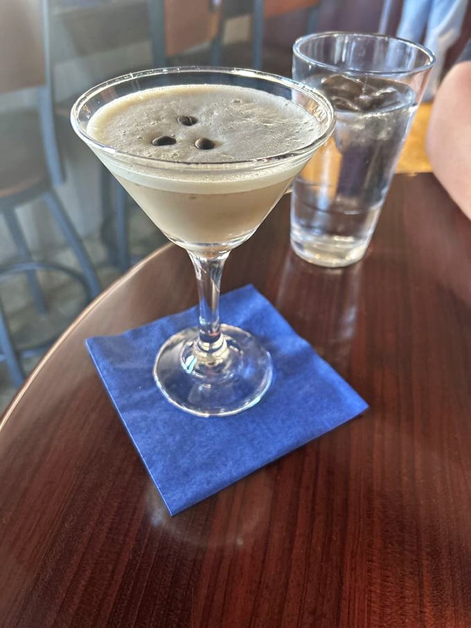 An espresso martini with three coffee beans floating like tiny boats—caffeine and alcohol joining forces for the perfect nightcap.