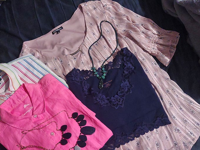 A textile still life of fashion possibilities – pink, navy, and patterns creating a secondhand symphony of style.