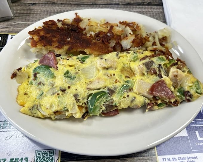 An omelet that's practically bursting with fillings, paired with crispy hash browns. This isn't breakfast—it's a celebration on a plate.