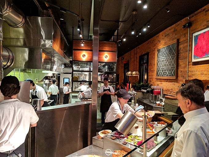 The open kitchen reveals the choreography behind the cuisine—a transparent testament to fresh ingredients and careful craftsmanship that builds trust with every order.