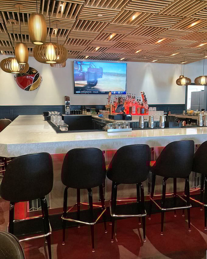 The bar doesn't just serve drinks—it's a marble-topped stage where liquid performances happen nightly under the watchful eye of wooden ceiling art.