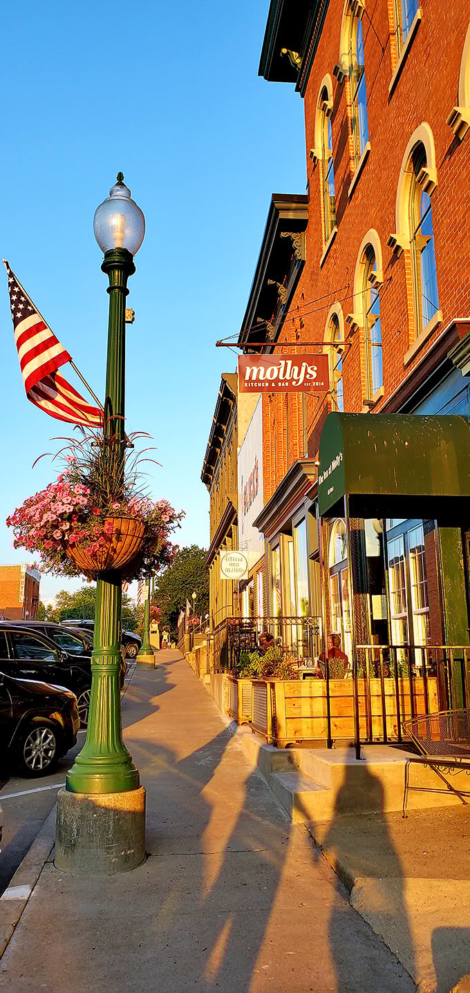 Molly's Kitchen & Bar captures that magical golden-hour light, when sidewalk planters, vintage lampposts, and American flags create peak small-town ambiance.