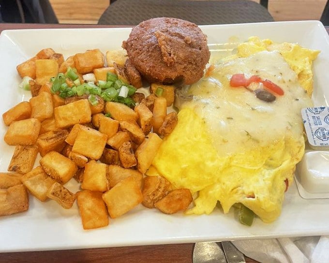 An omelet that's achieved the impossible breakfast trifecta: beautiful to behold, generous in portion, and served with potatoes that steal the show.