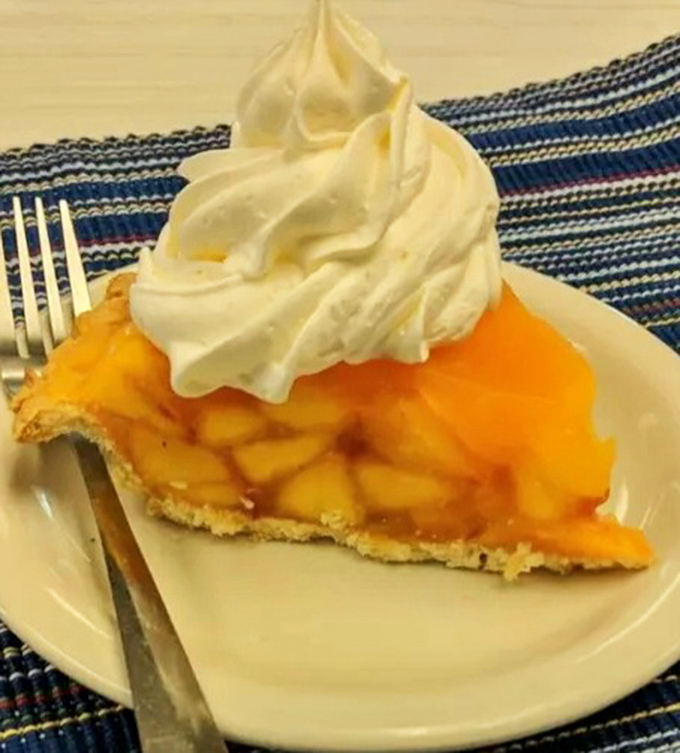Peach pie that makes you want to write poetry. That whipped cream cloud isn't just a topping—it's the perfect dance partner.