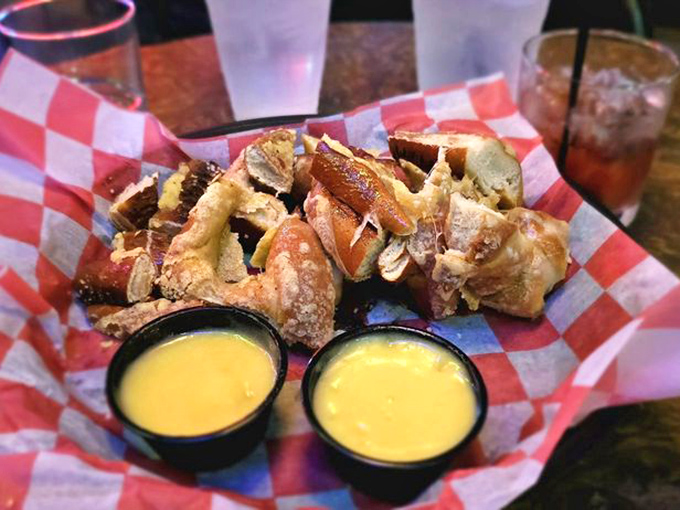 These aren't just pretzels; they're golden-brown twisted treasures guarded by twin sentinels of liquid gold dipping sauce.