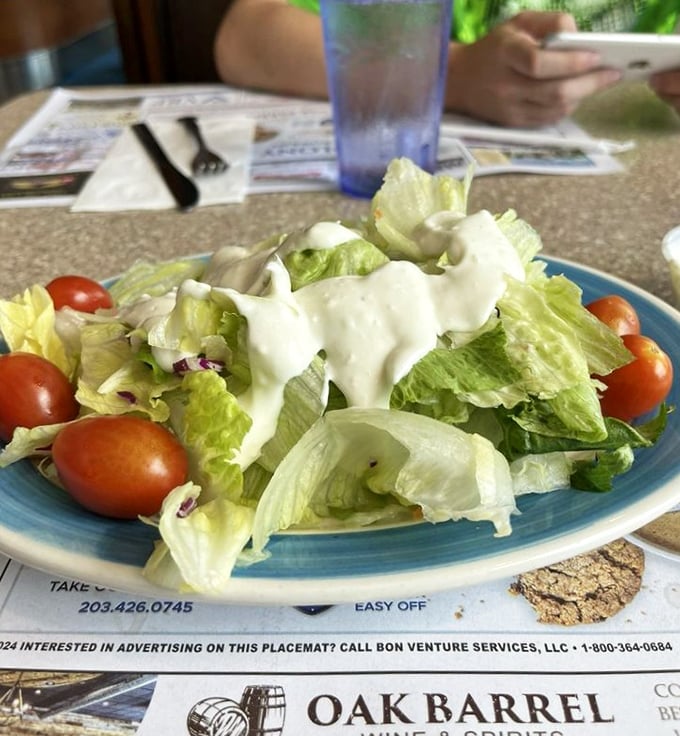 Even the garden salad gets the royal treatment—crisp greens, ripe tomatoes, and dressing applied with a generous hand that says "Yes, vegetables can be exciting."