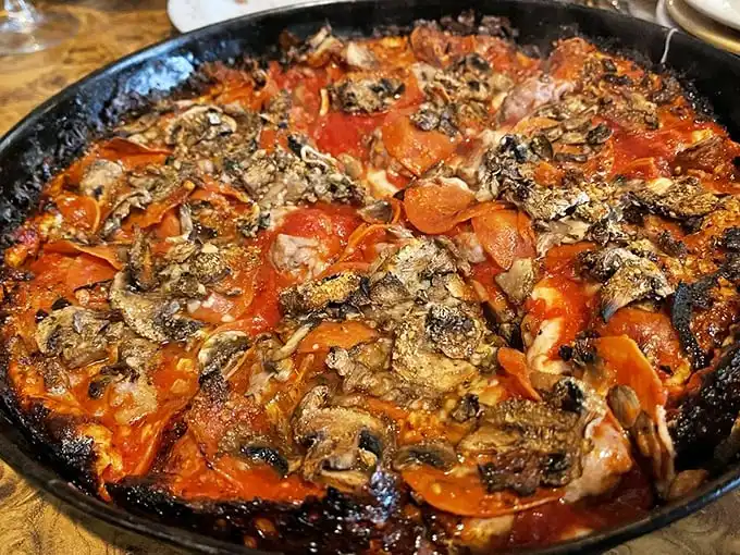 The holy trinity of pizza toppings—sausage, pepperoni, and mushrooms—having a flavor party in a perfectly seasoned cast iron pan.
