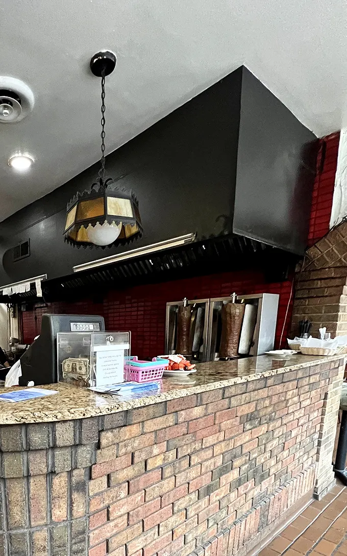 Behind this unassuming counter, culinary magic happens with the efficiency of a Greek orchestra—each movement precise and purposeful.