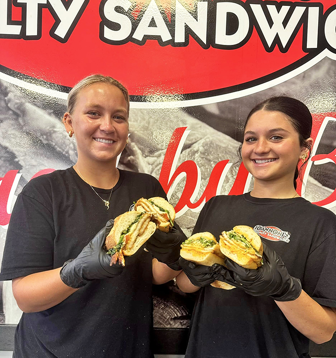 The sandwich artists at work—where black gloves signal serious business and smiles signal genuine pride in their craft.