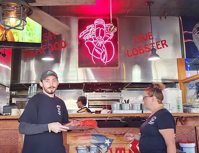 Under that neon lobster sign, kitchen magic happens. These folks aren't just staff; they're guardians of authentic New England tradition.