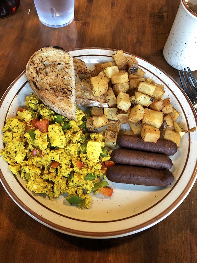 A hearty breakfast plate that says "You won't be hungry again until dinner"—scrambled eggs with veggies, perfectly seasoned potatoes, and sausage links standing at attention.