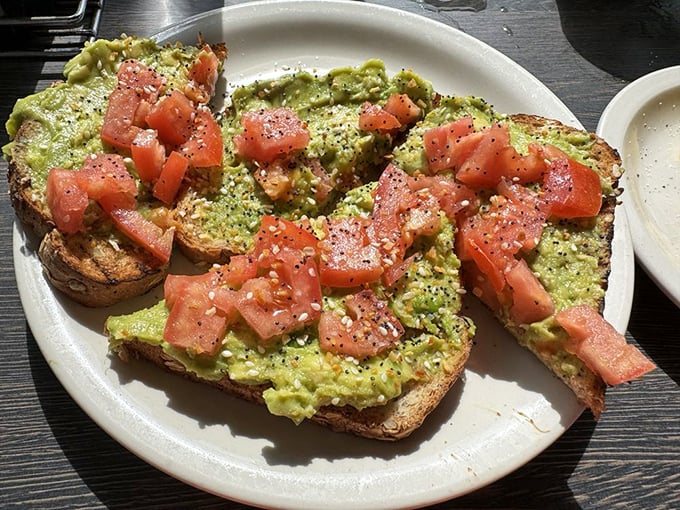 Avocado toast that doesn't require a second mortgage – just fresh avocado, diced tomatoes, and everything bagel seasoning on hearty bread.