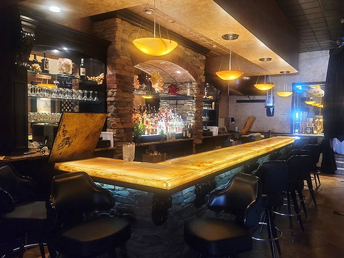 The bar isn't just a place to wait for your table – it's a destination itself, with its golden glow and stone accents inviting lingering conversations.