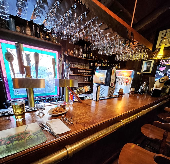 A bar that gleams with promise under stained glass light. Those wine glasses hanging above aren't just storage—they're possibilities waiting to happen.