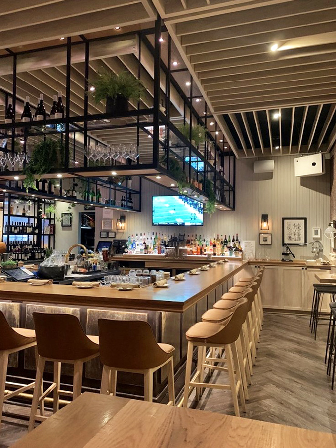 The bar isn't just where you wait for your table—it's a destination with hanging wine glasses that promise good decisions ahead.