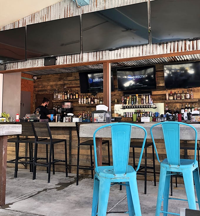 A bar built for stories—where weathered wood meets turquoise chairs, and bartenders mix drinks with the casual precision of people who understand vacation time is precious.