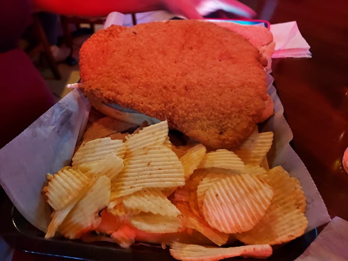 The breaded pork tenderloin sandwich—Indiana's unofficial state food—hangs dramatically over its plate like a crispy, delicious eclipse of the bread.