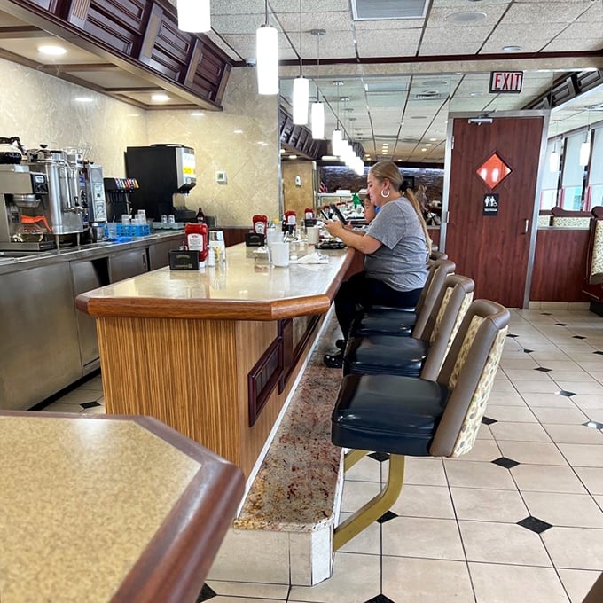 The counter—where regulars perch like birds on a wire, watching the morning unfold over steaming mugs of coffee.