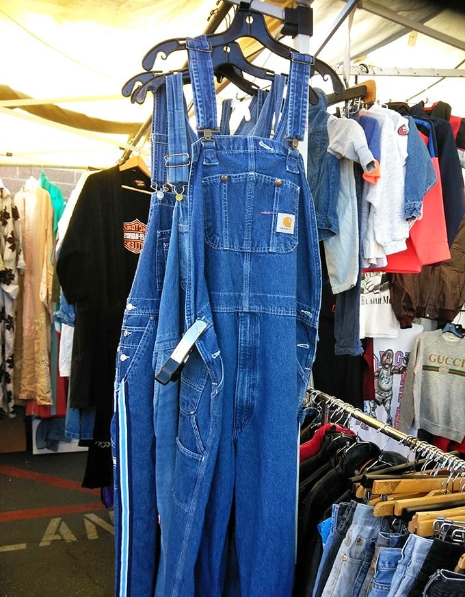 Classic Carhartt overalls hanging proudly among vintage threads—the uniform of America's working class now coveted by fashion-forward urbanites and authentic laborers alike.