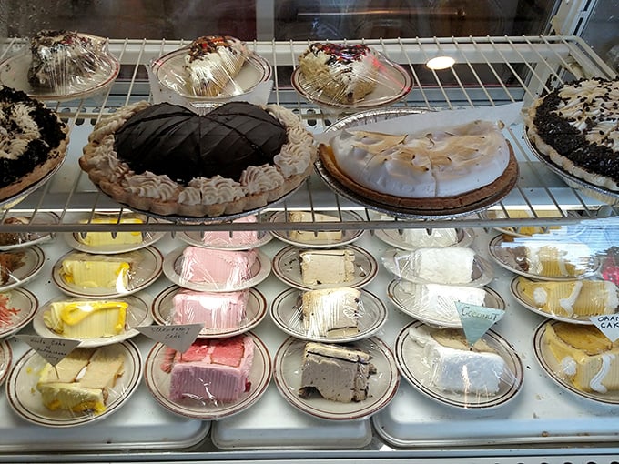 The dessert case—a glass-fronted museum of American sweet tooth archaeology. Each pie and cake tells a story of tradition and indulgence.