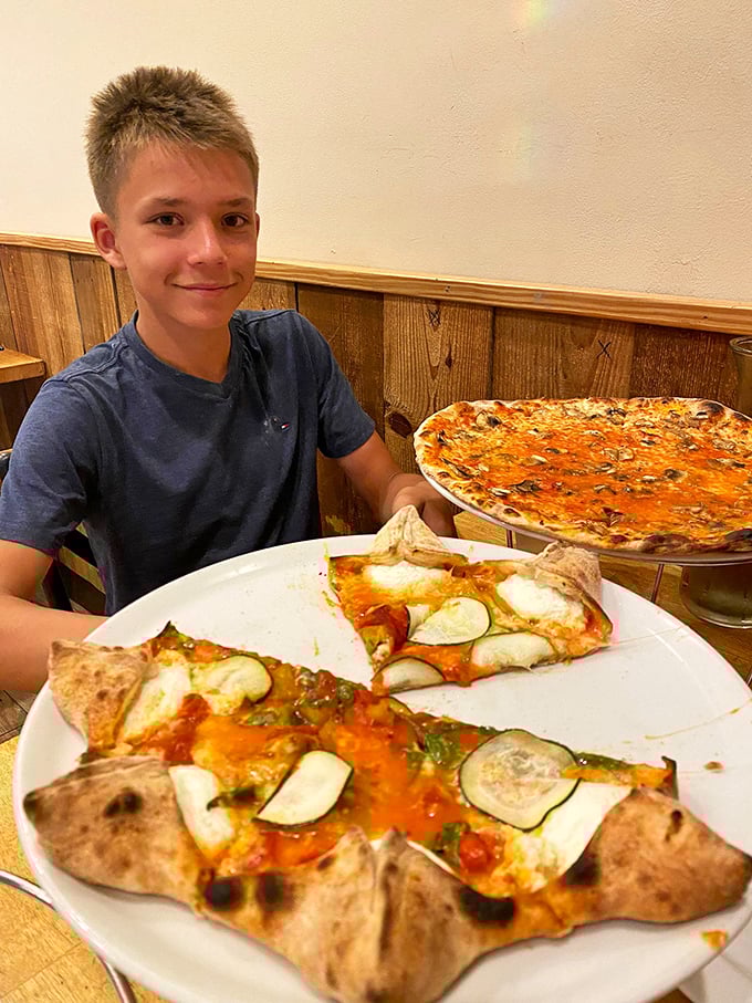 That look of pizza anticipation is universal—whether you're eight or eighty, there's nothing like the moment before that first perfect bite.