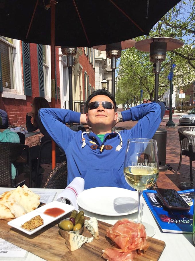 A patron enjoying the perfect trifecta – sunshine, wine, and a charcuterie board that would make any Italian grandmother nod in approval.