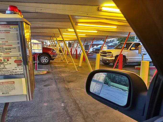 Drive-in dining from the driver's seat—where your car becomes the best table in the house. That menu board has witnessed more food decisions than a grocery store checkout line.