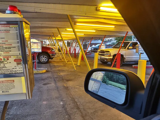 Drive-in dining from the driver's seat—where your car becomes the best table in the house. That menu board has witnessed more food decisions than a grocery store checkout line.