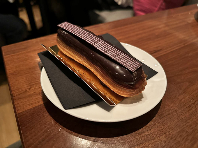 This éclair isn't just chocolate-topped pastry—it's a structurally perfect vessel delivering pure joy straight to your pleasure centers. Worth every calorie.