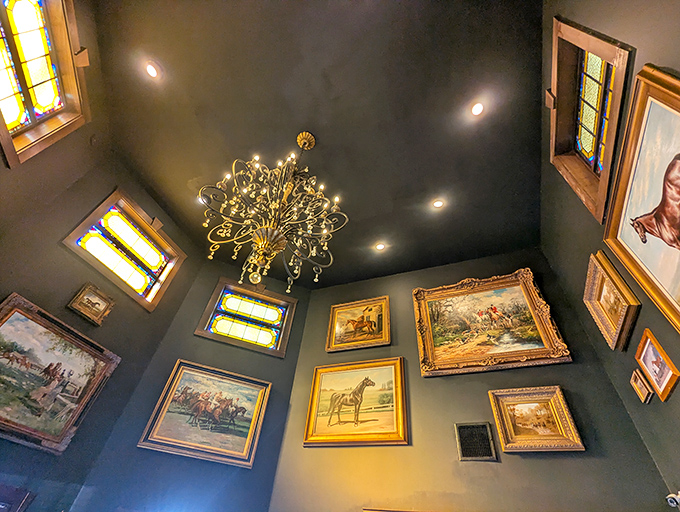 A gallery wall of equestrian art beneath a starburst chandelier. It's like being inside a very tasteful Kentucky Derby enthusiast's dream home.