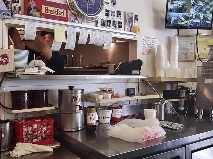 The kitchen pass—where orders hang like promises and the choreography of short-order cooking unfolds with practiced precision.