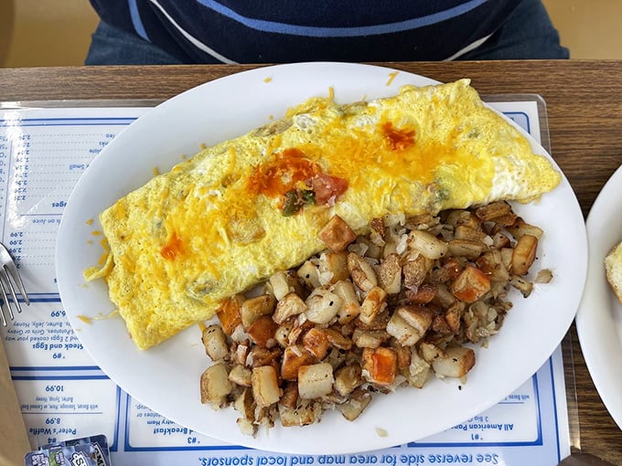 An omelet that's been folded like a letter containing good news, alongside perfectly diced potatoes. Cheese pulls stretch with each forkful like edible sunshine.
