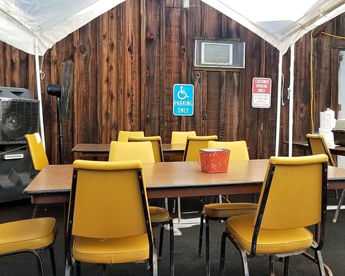 Yellow chairs against rustic wood paneling create an outdoor dining space that feels like eating at a friend's cabin – if your friend were an excellent cook.
