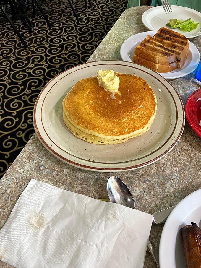 A pancake so perfectly golden it belongs in Fort Knox. That pat of butter melting in the center is performing a slow dance that deserves its own soundtrack.
