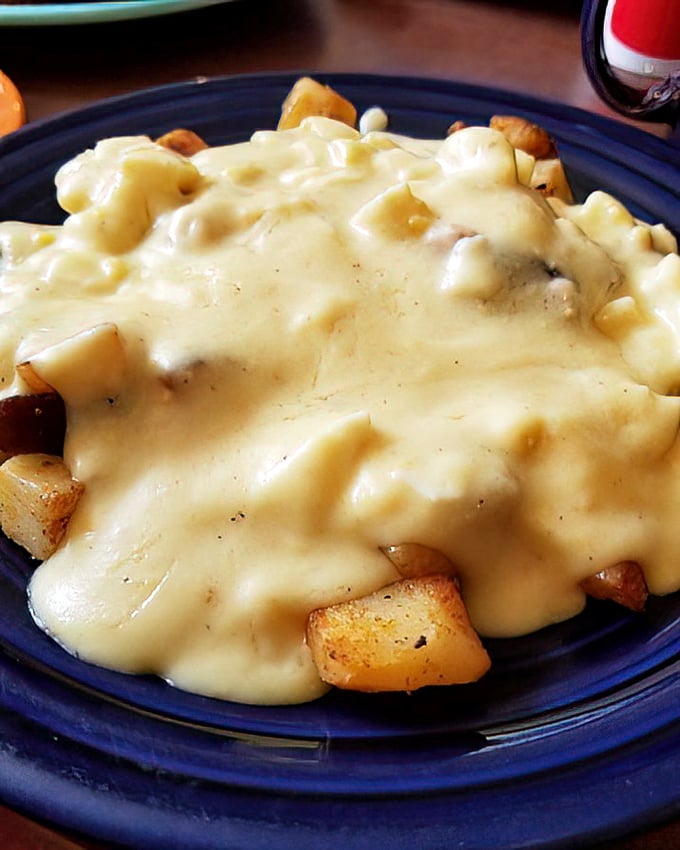 Home fries swimming in cheese sauce—a glorious indulgence that makes vegetables merely an afterthought.