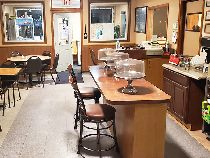 The counter seating offers front-row tickets to the quiet efficiency of a small-town restaurant. Those cake stands aren't just storage—they're pedestals for upcoming joy.