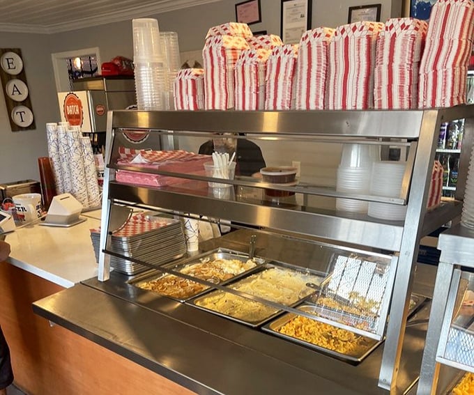 The serving line—where dreams come true and diets go to die. Each metal tray holds the promise of smoky perfection.