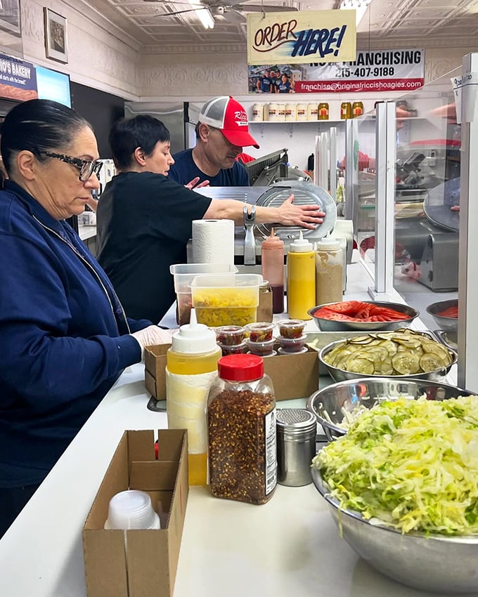 Behind the counter, the sandwich assembly line operates with the precision and focus of a NASA launch—fresh ingredients awaiting transformation.