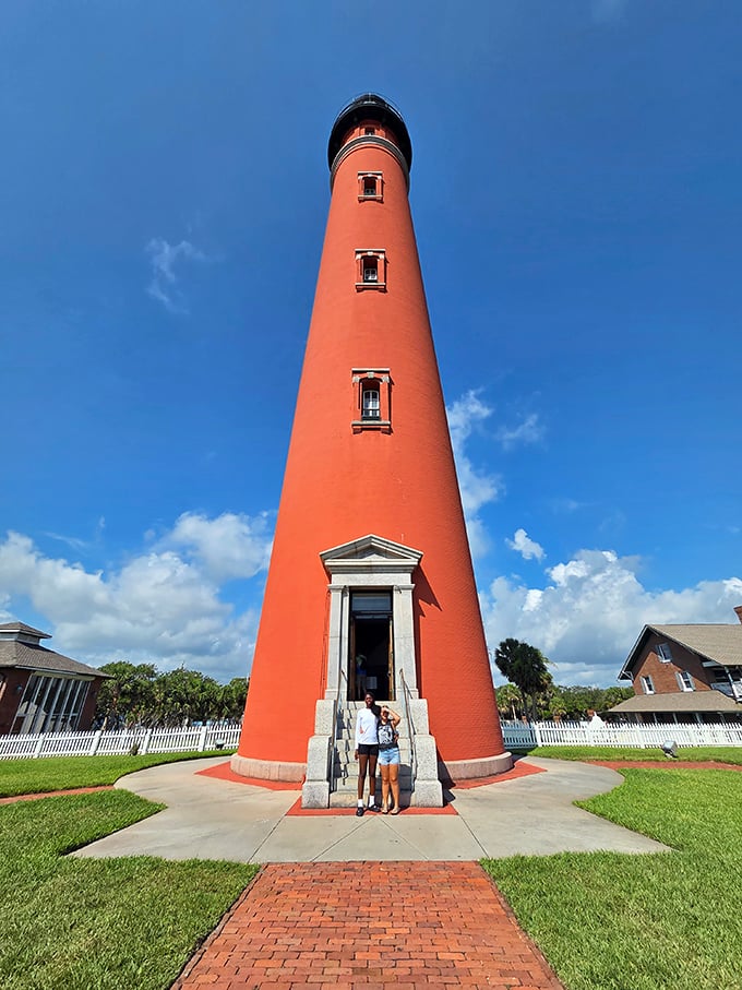The ultimate "we were here" moment—two visitors providing scale to this towering maritime sentinel that makes humans look like maritime action figures.